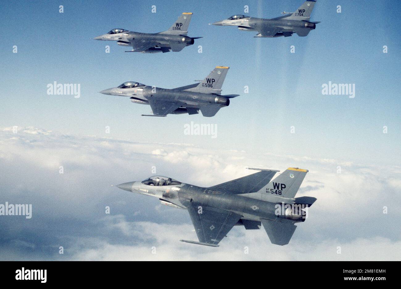 An air-to-air left side view of four F-16 Fighting Falcon aircraft in ...