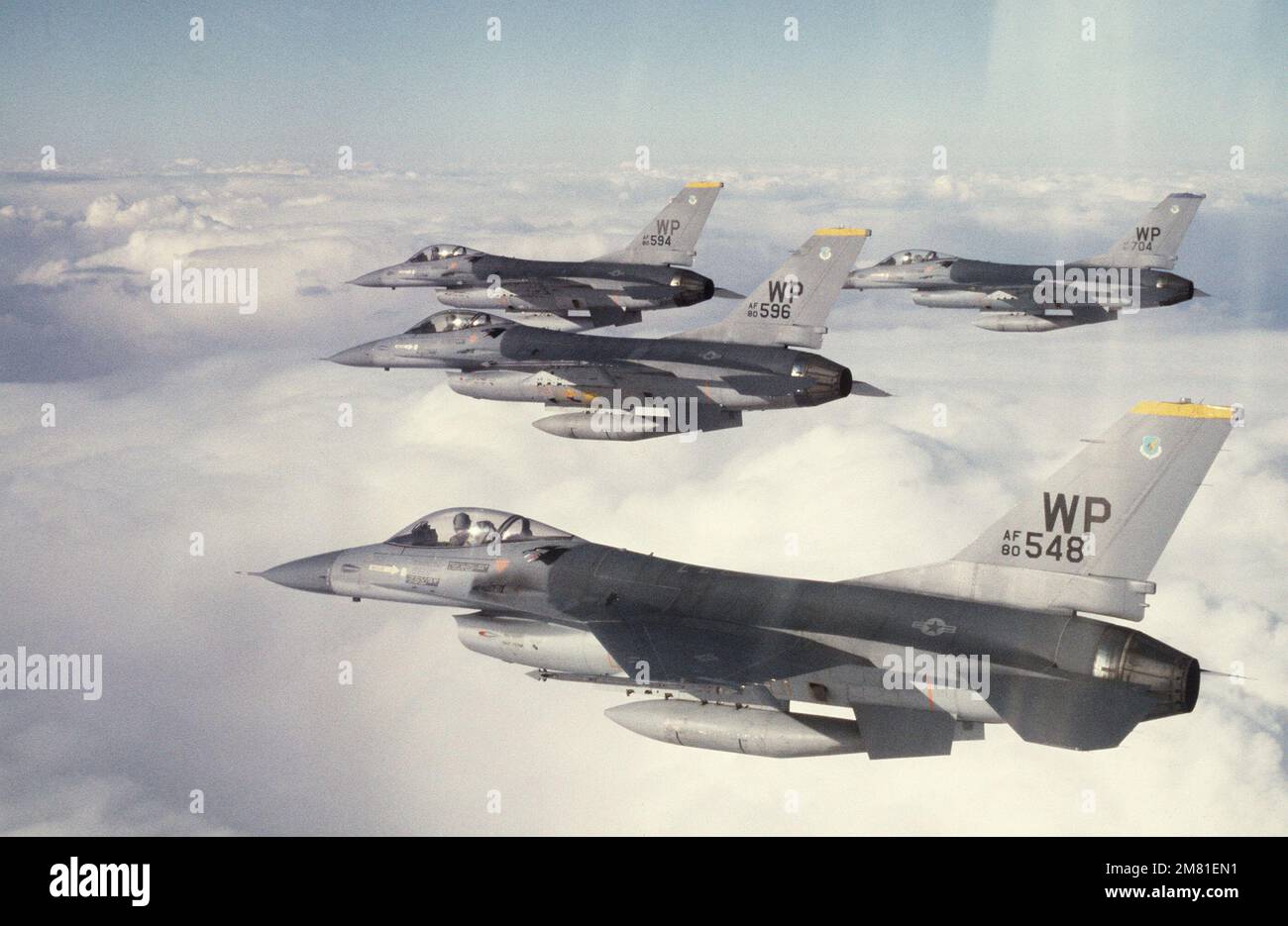 An air-to-air left side view of four F-16 Fighting Falcon aircraft in ...
