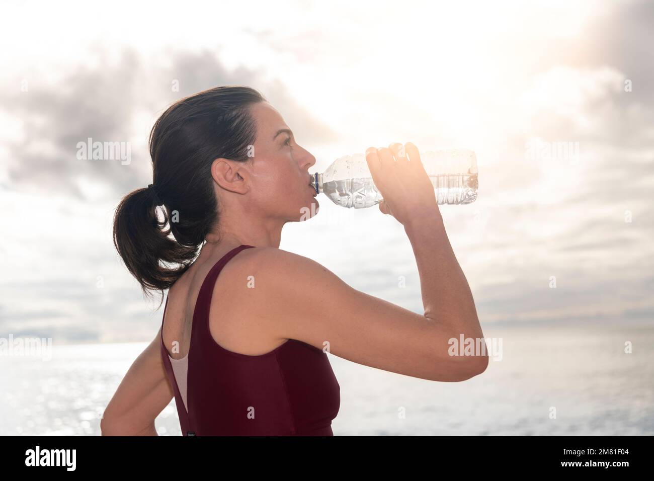 Sporty woman drinking water after exercising on a hot day. Female ...