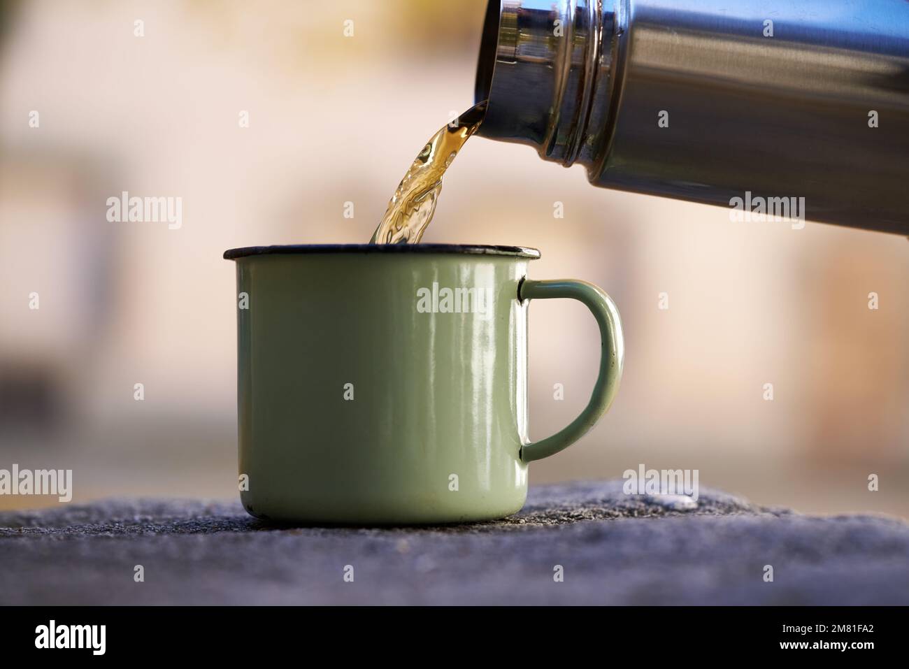 Pouring tea from a vacuum flask into cup outdoors Stock Photo - Alamy