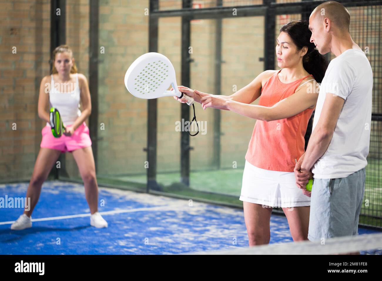 Female trainer teaches man to play padel on tennis court Stock Photo ...