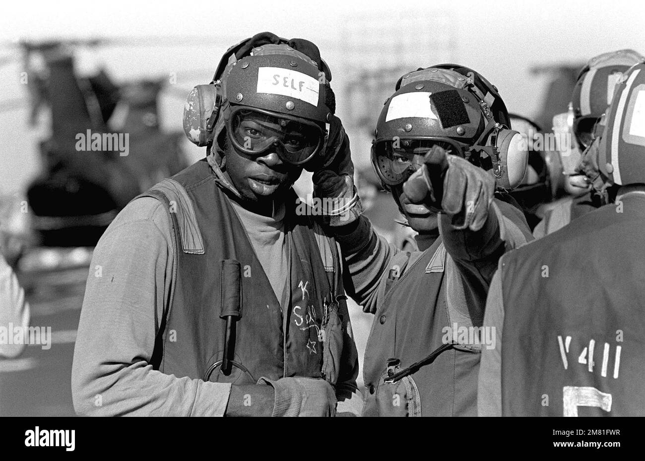 Two flight deck crewmen discuss their duties aboard the amphibious ...