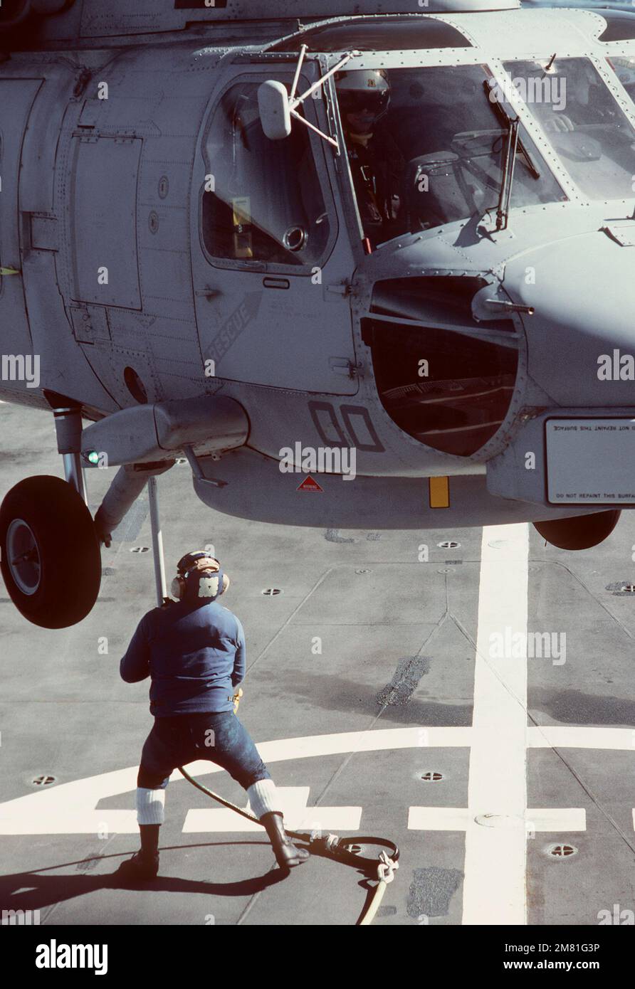 A crewman attaches a cargo net to a hook under the Navy's first ...