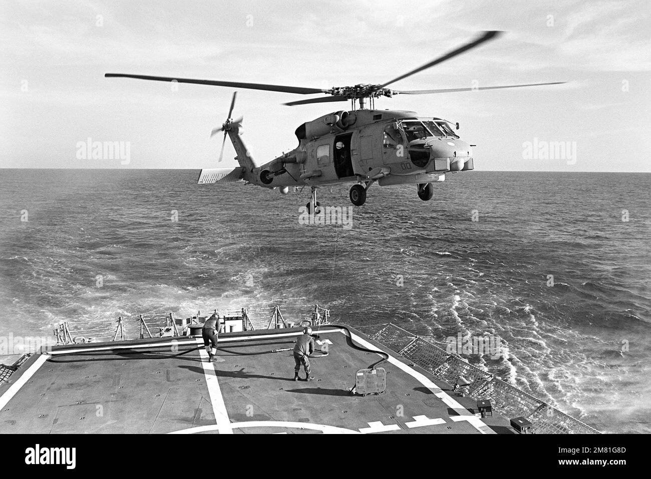 Crewmen prepare to connect an in-flight refueling line to the hoist of ...