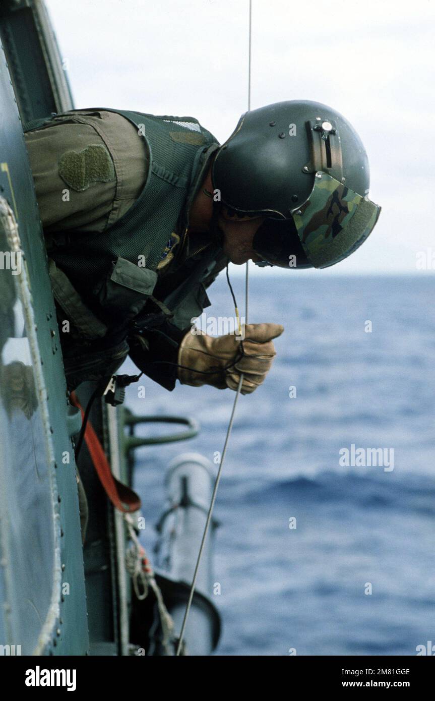The flight engineer aboard an HH-53 helicopter watches the cables as ...