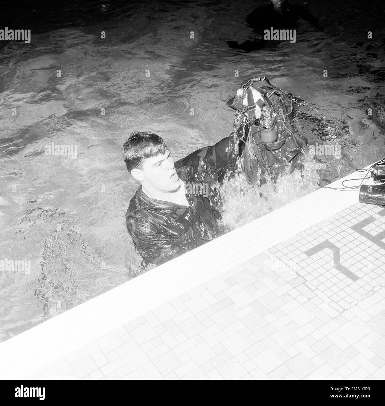 A fully-clothed cadet climbs out of the pool with his equipment during ...