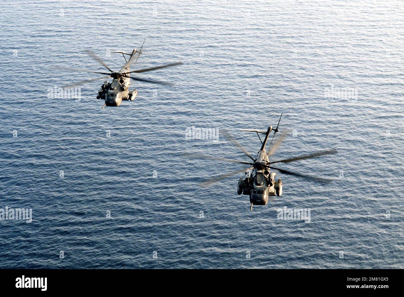 Two Helicopter Combat Support Squadron 4 (HC-4) CH-53E Super Stallion helicopters pass over the ...