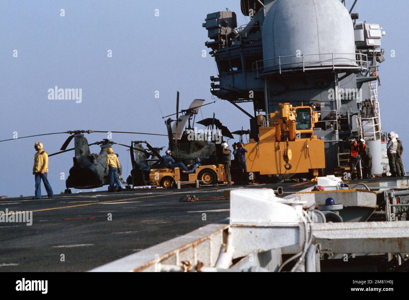 Flight deck crew members stand by during helicopter operations on the ...