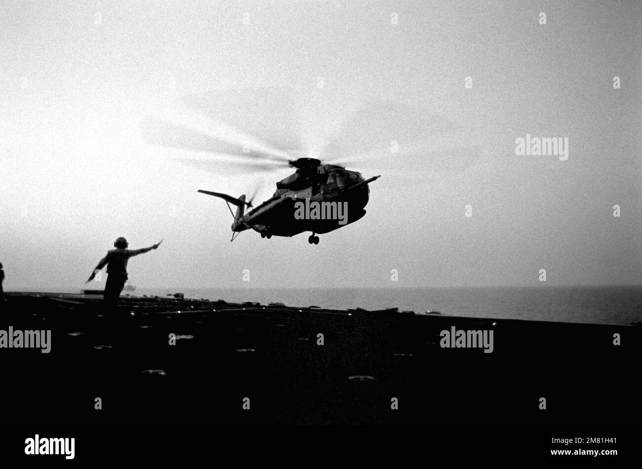 A flight deck crew member signals to the pilot of a Helicopter Combat ...