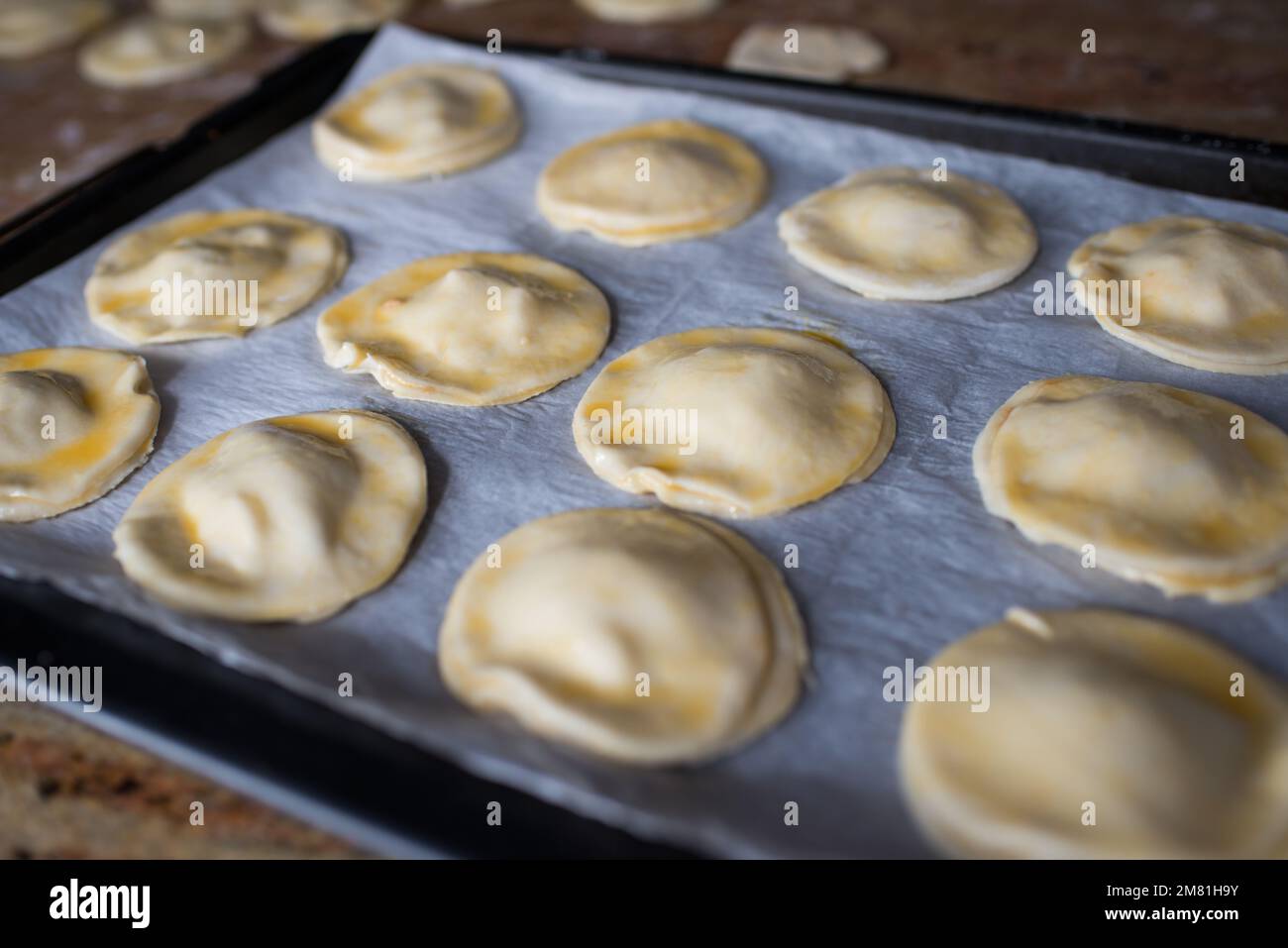 Raw puff pastry dumplings on a oven tray. Close up Stock Photo - Alamy