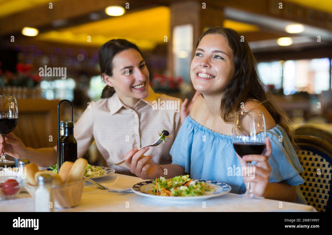 Two positive female best friends drinking wine in restaurant Stock ...