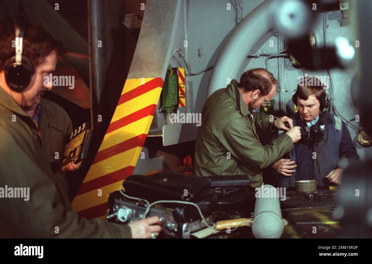 An audiovisual team prepares a crewman for his part in a film by ...