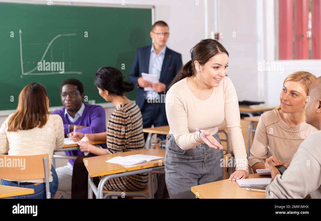 Positive students are talking about homework at desk Stock Photo - Alamy