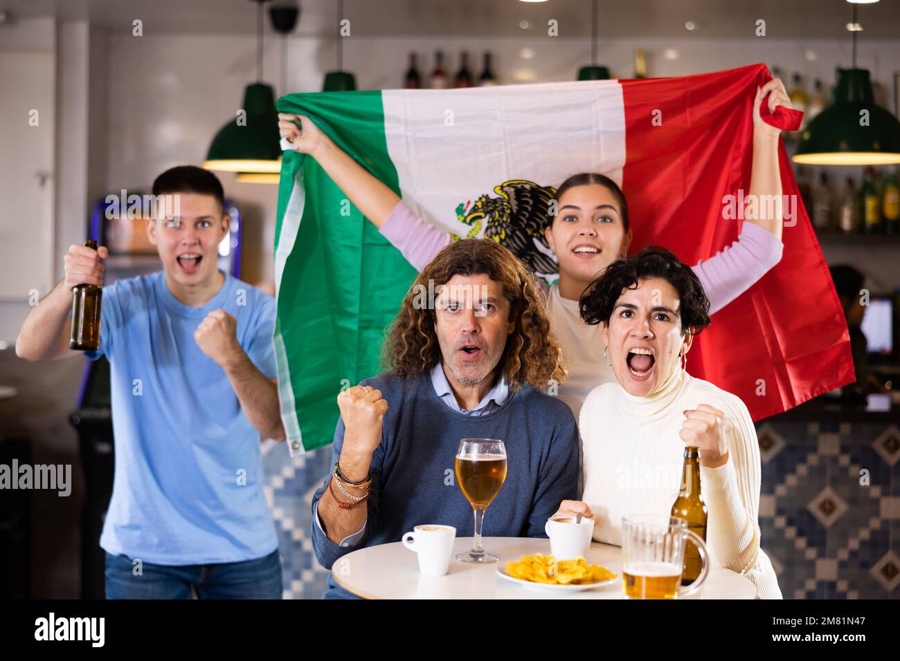Company of emotional young adult sports fans supporting Mexican team ...