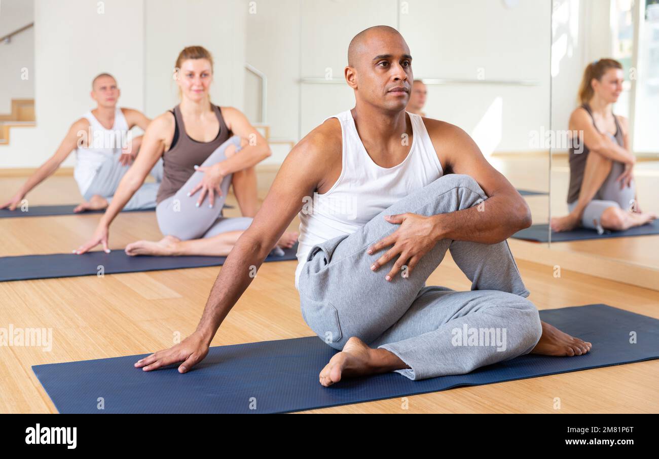 Sporty people practicing various yoga positions during training indoors ...