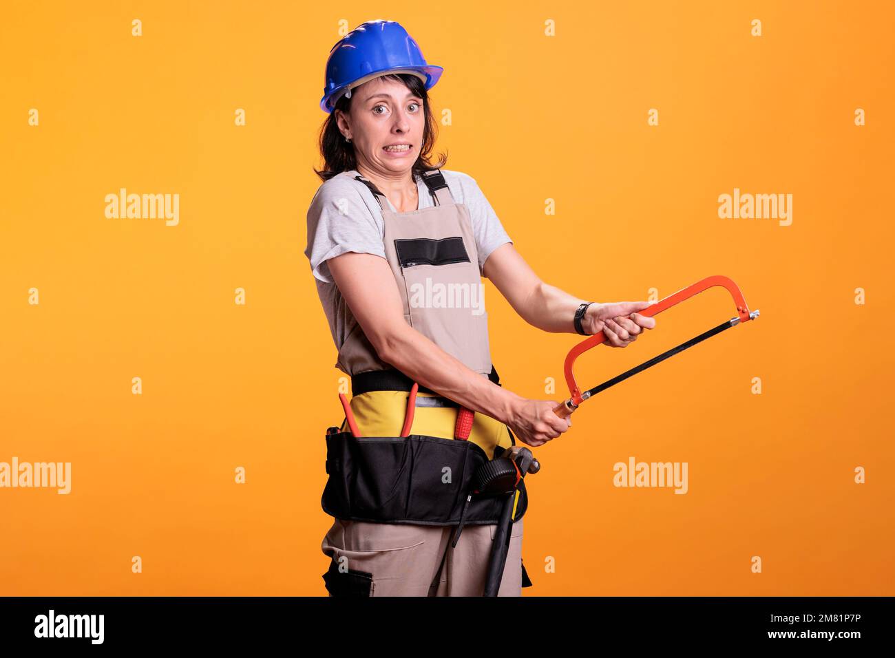 Woman construction worker holding hand saw and using tool belt, working ...