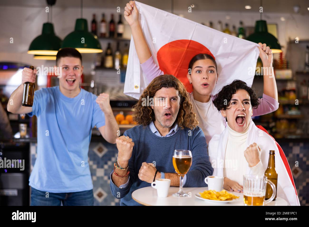Enthusiastic company of young adult sports fans waving flag of Japan ...