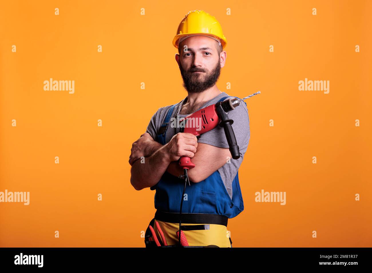 Happy building contractor holding power drill gun and posing in studio ...