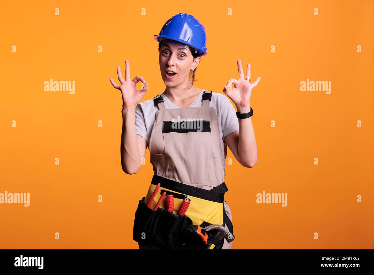 Young female contractor doing okay good symbol in studio, wearing ...