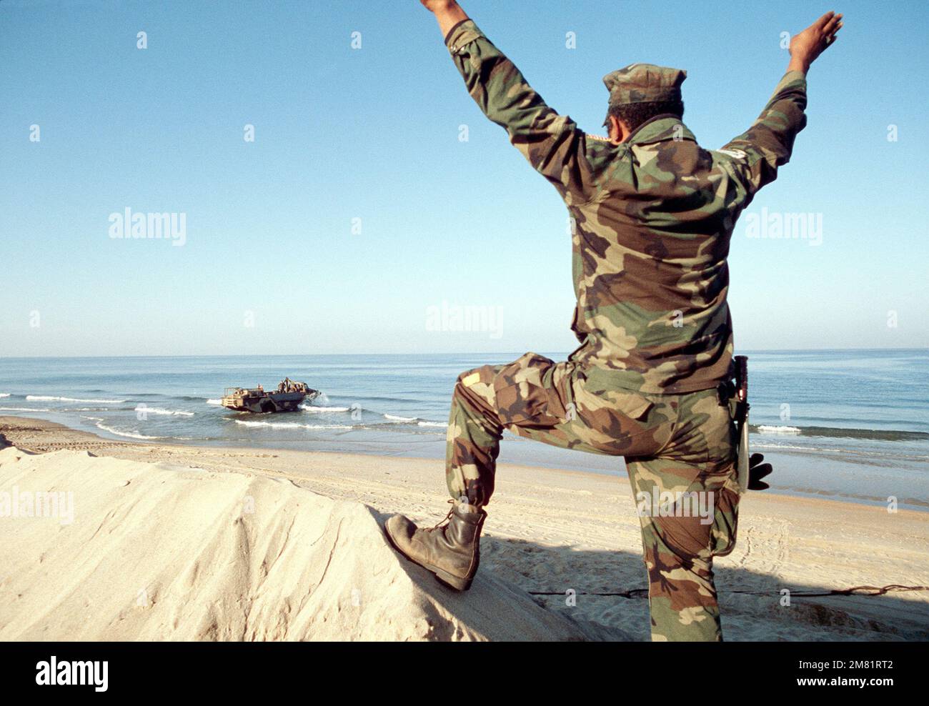 A beachmaster from the 22nd Marine Amphibious Unit signals to a lighter ...