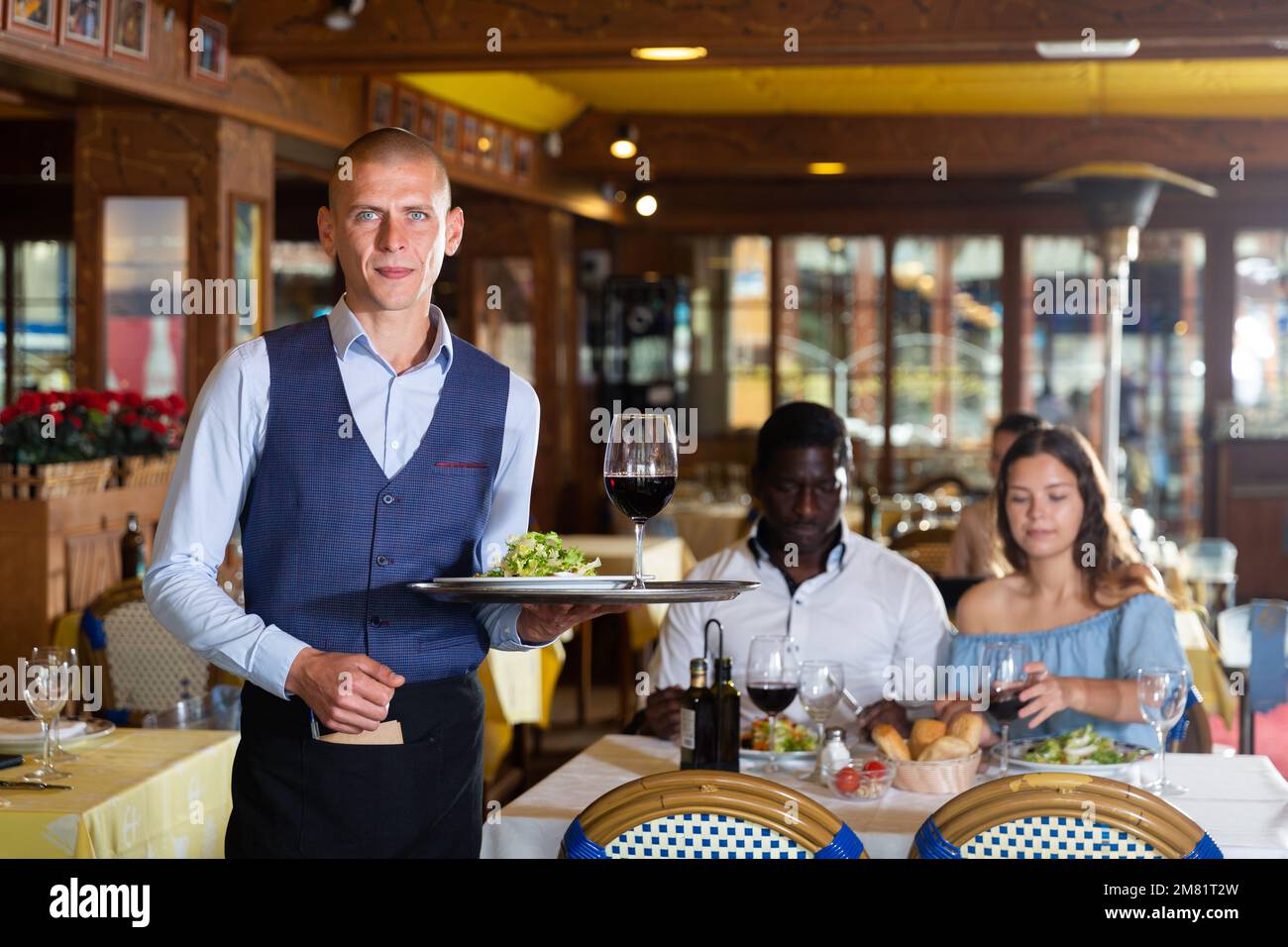 Professional young smiling waiter holding serving tray Stock Photo - Alamy