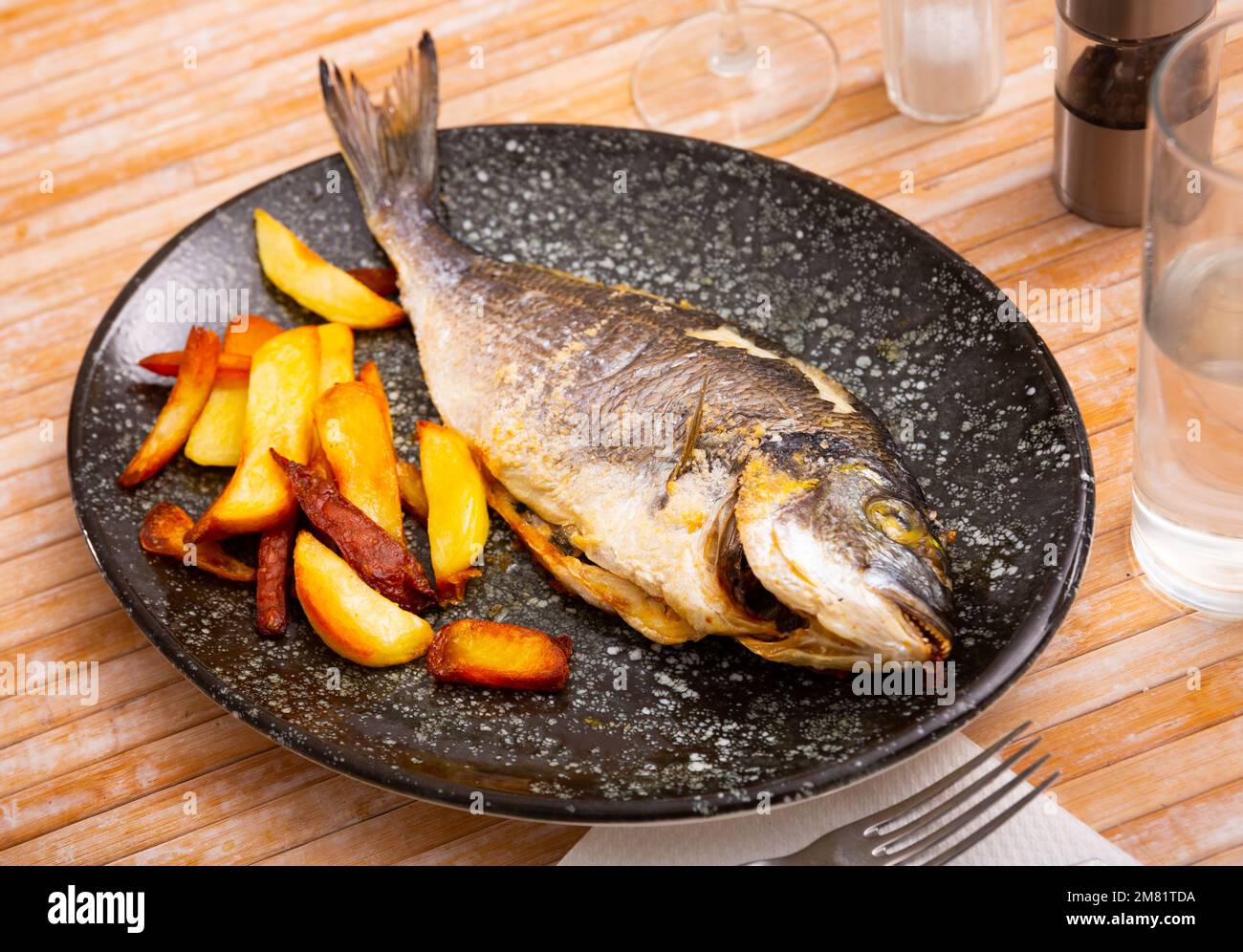 Grilled gilthead bream with side dish of baked potato Stock Photo - Alamy