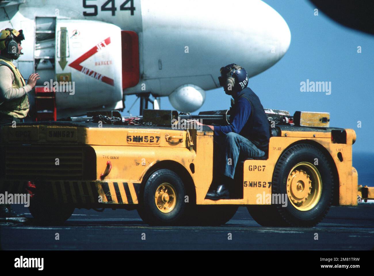 A flight deck crewman operates an MD-3 tow tractor on the flight deck ...