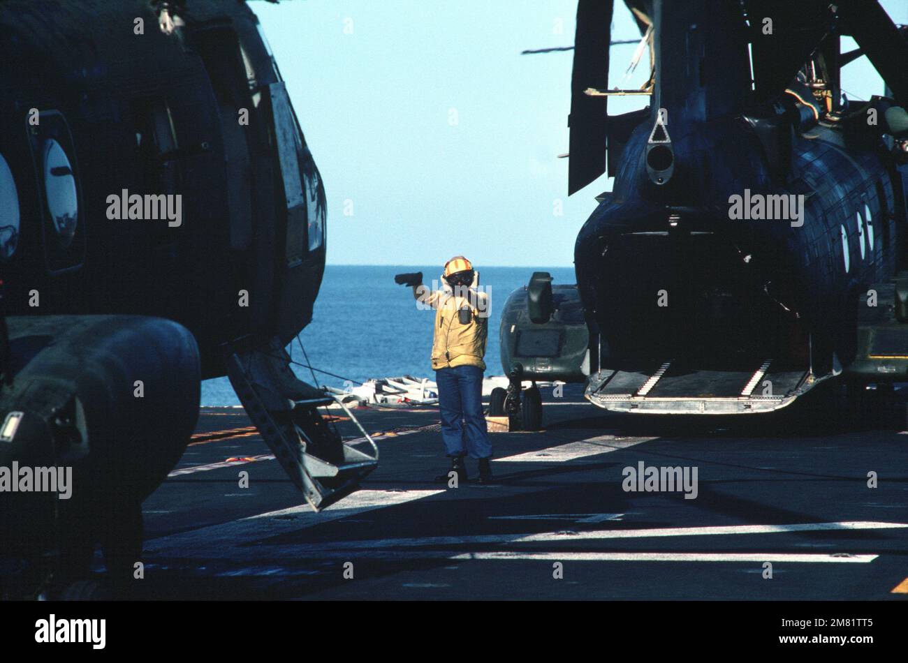 A helicopter launch petty officer directs flight deck operations aboard ...