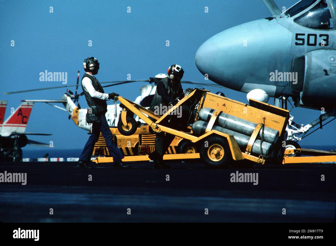 Flight deck crewmen transport an NAN-2 nitrogen servicing unit across ...