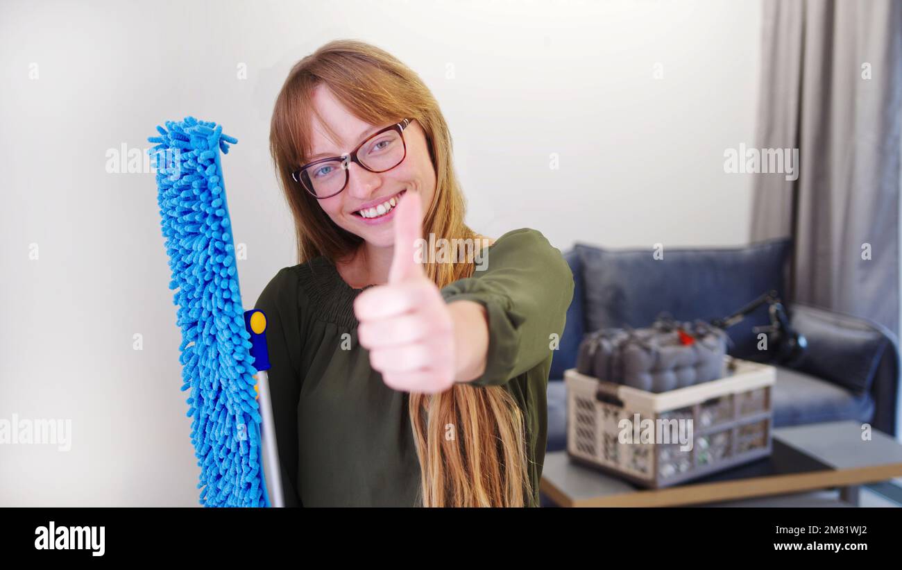 ginger-haired woman with glasses and toothy smile holding a blue ...