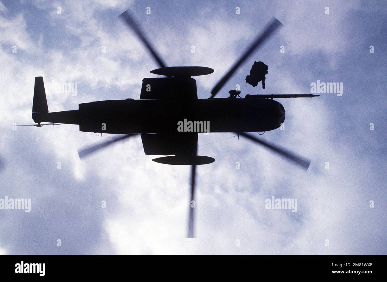 An HH-3C helicopter lowers a pararescueman on a penetrator cable during ...