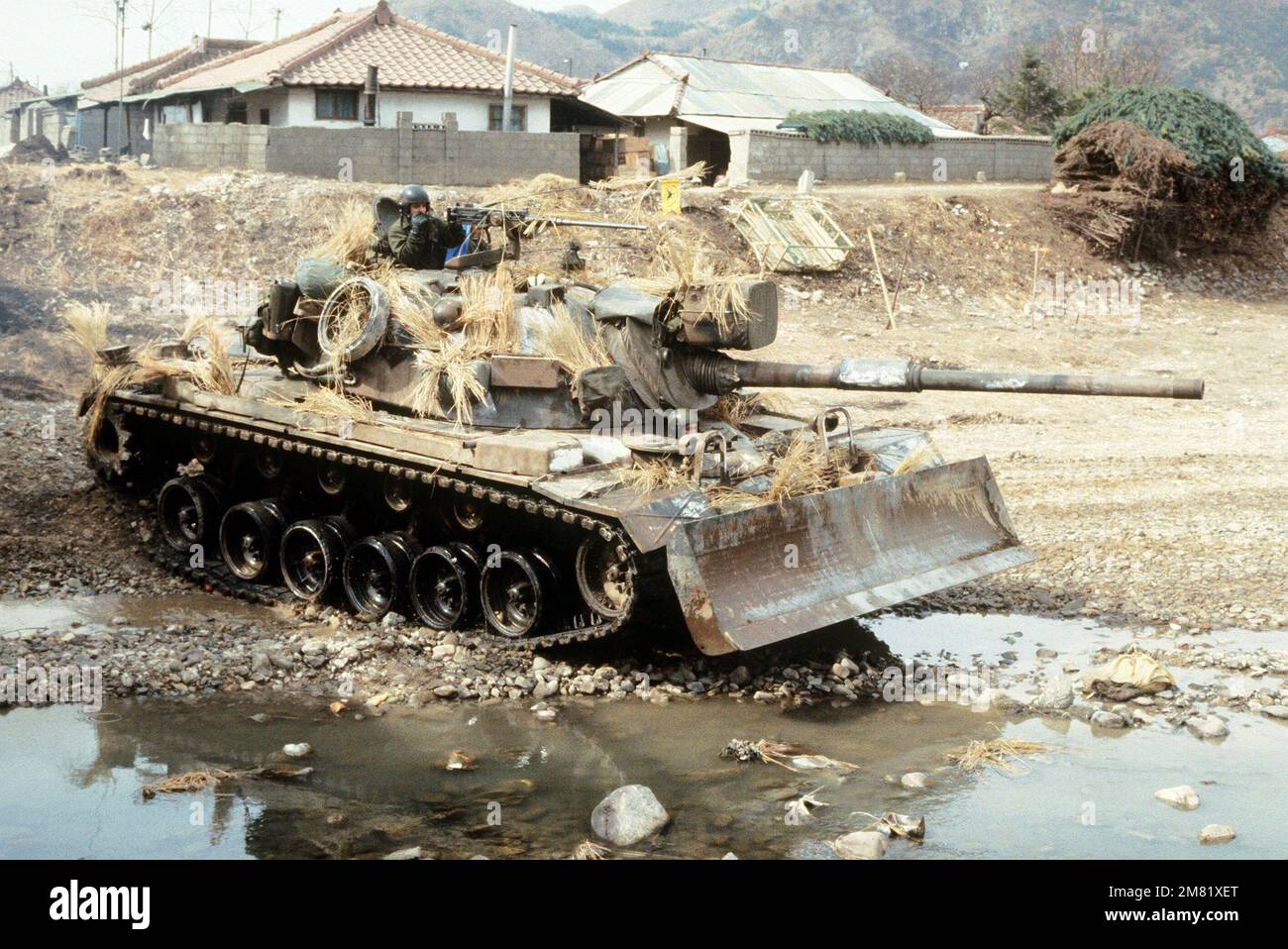 An M60 main battle tank, equipped with a bulldozer blade, prepares to ...
