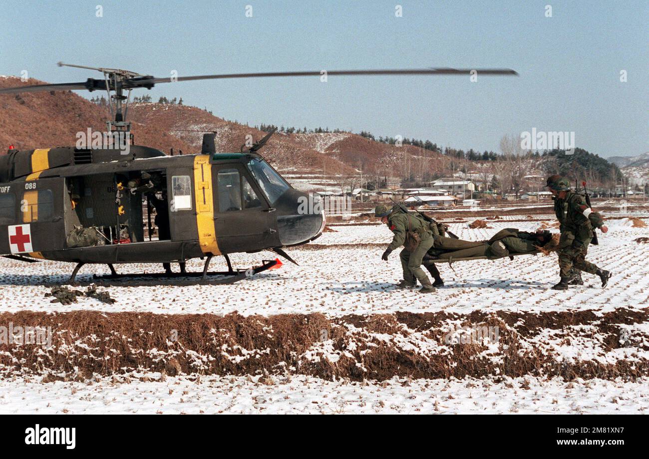 Second Medical Battalion medics carry a "casualty" toward a UH-1 ...