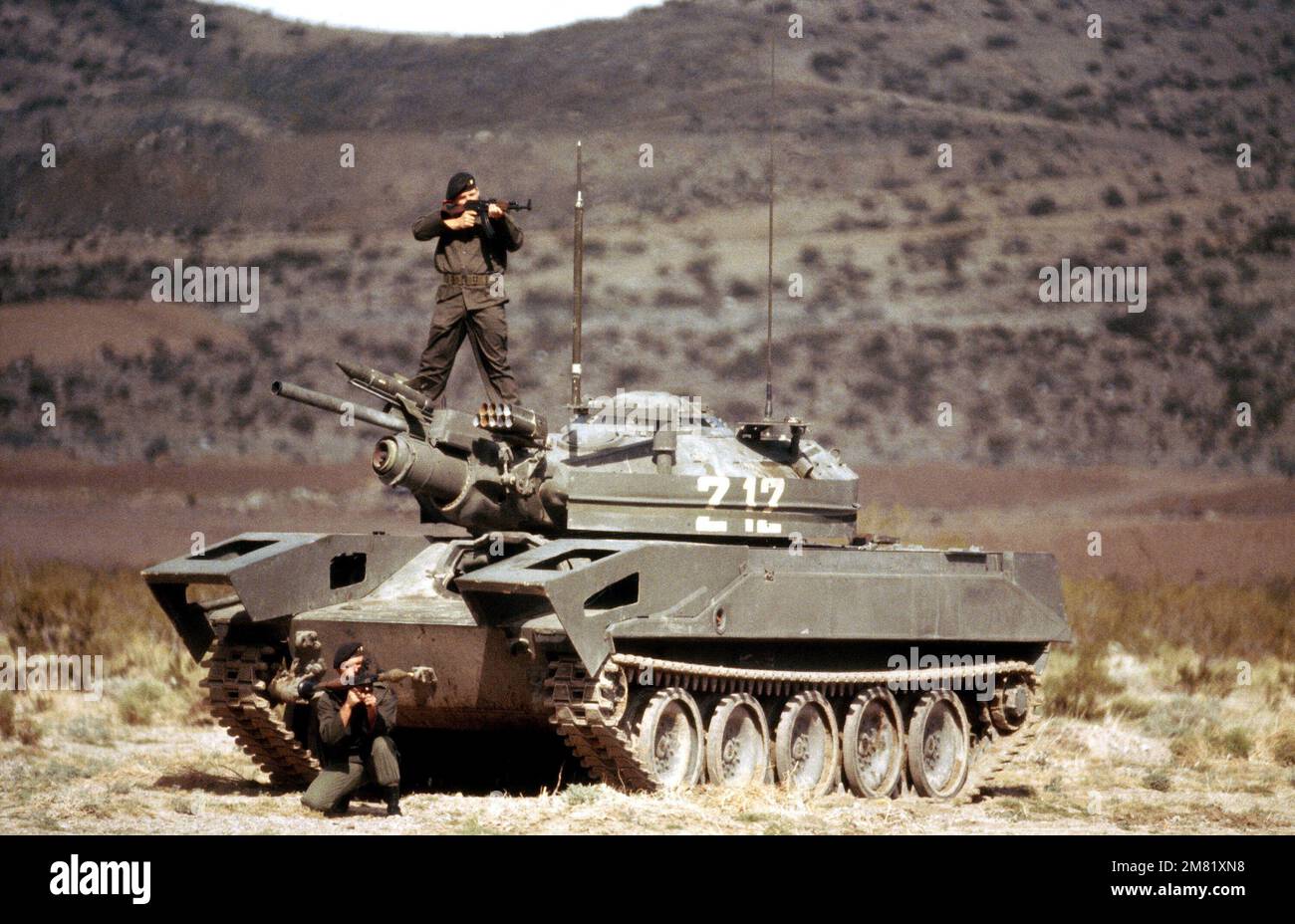 An infantryman fires a rifle from the turret of an M551 light tank with ...