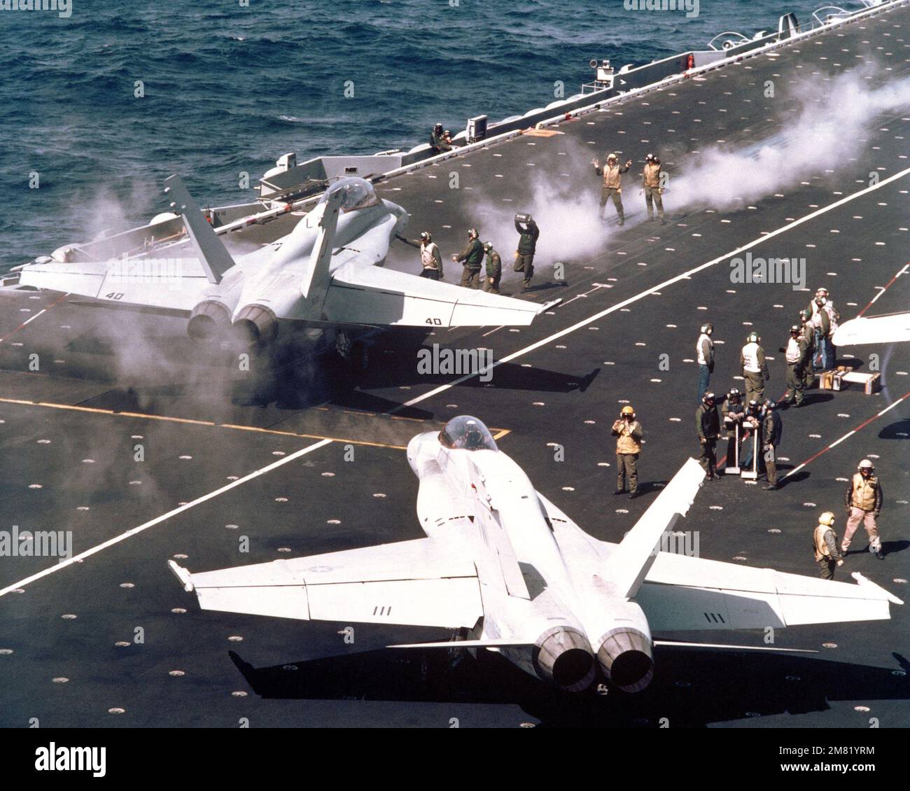 Two F/A-18 Hornet aircraft are prepared for launching from the flight ...