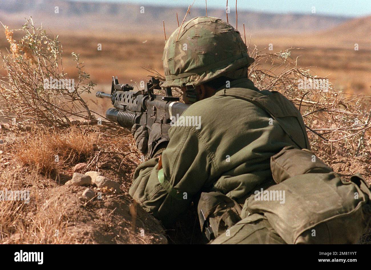 A soldier aims his M-16A1 rifle, equipped with an M-203 grenade ...