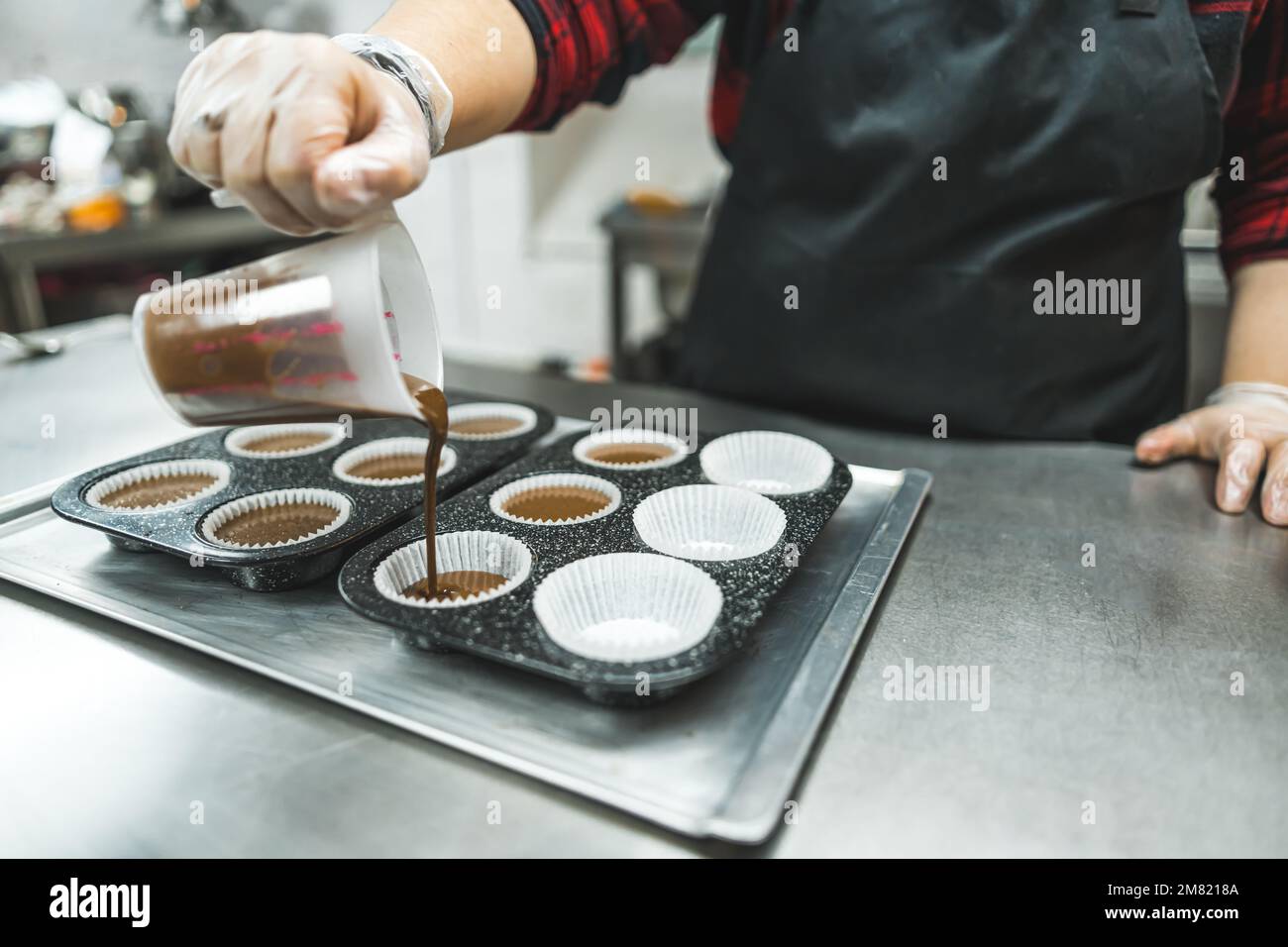 Cupcake baking. Professional pastry chef pouring chocolate batter into ...