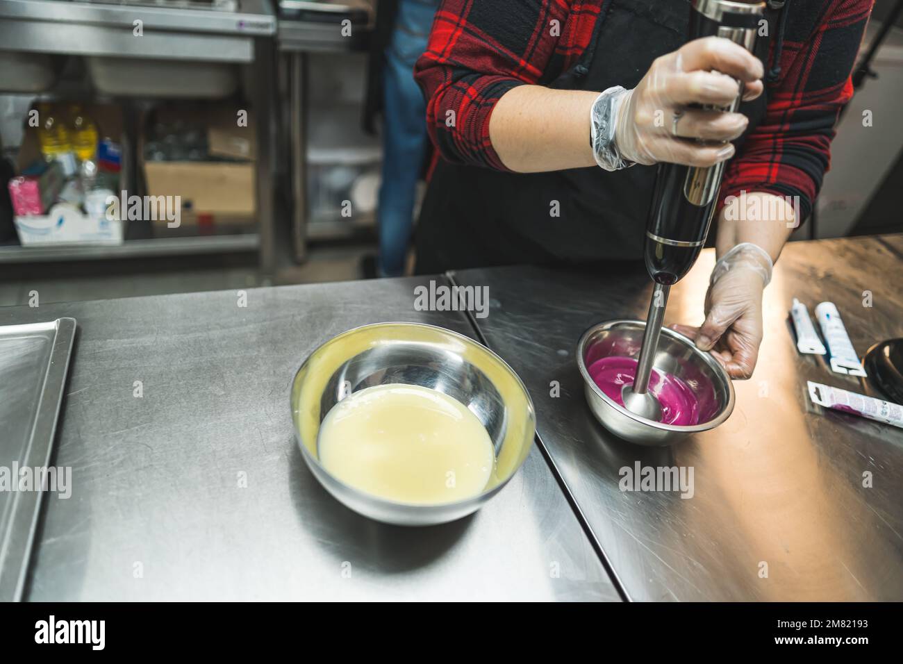 Unrecognizable female pastry chef prepares a pink icing for a cake ...