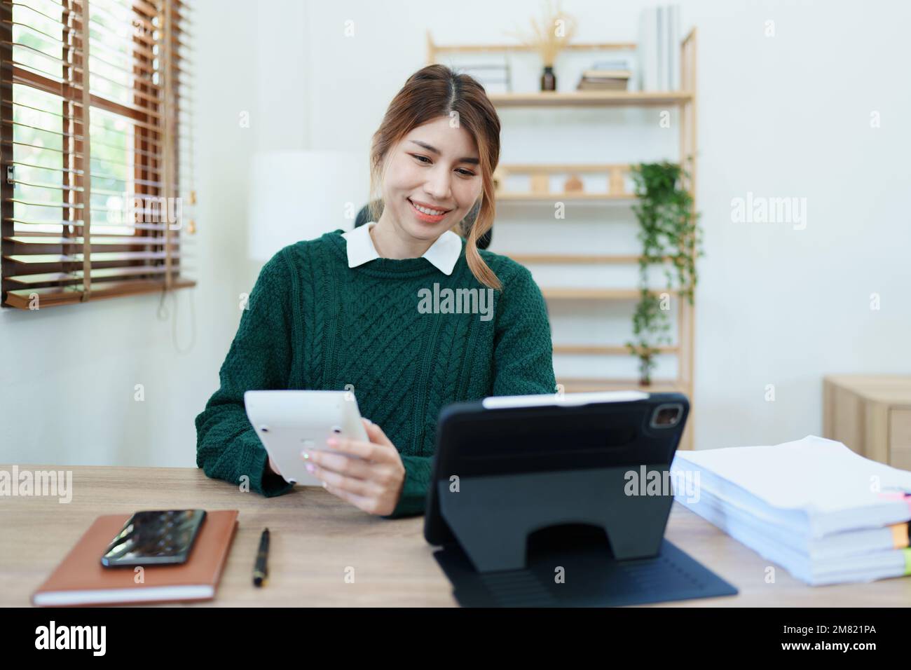 business owner or Asian female marketers are using calculator to ...