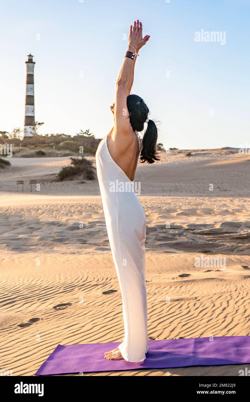 Side view of a female standing with arms up doing sun salutations Stock ...