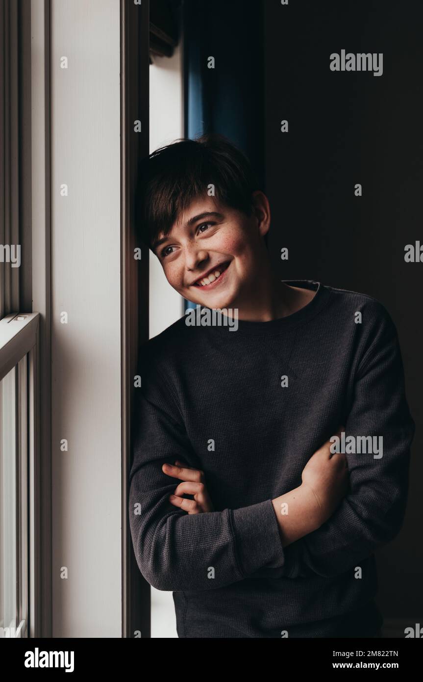 Portrait of happy smiling tween boy standing beside a window Stock ...