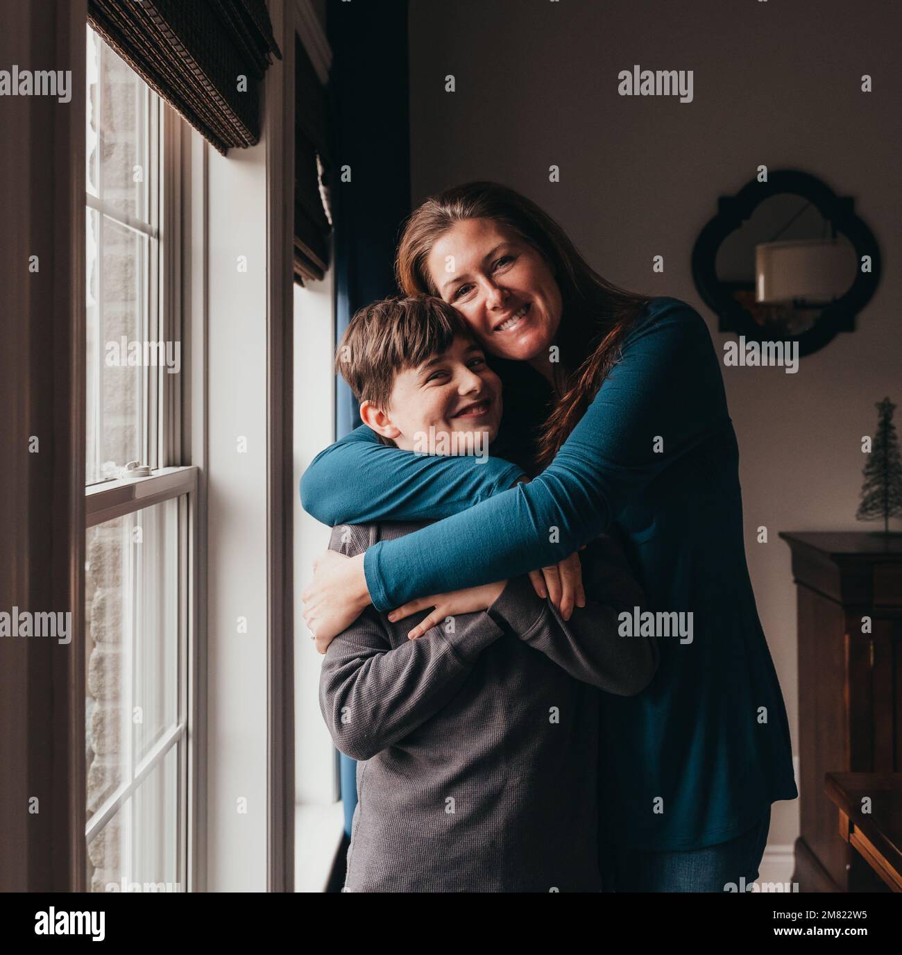 Happy mother and pre-teen son hugging inside at home Stock Photo - Alamy