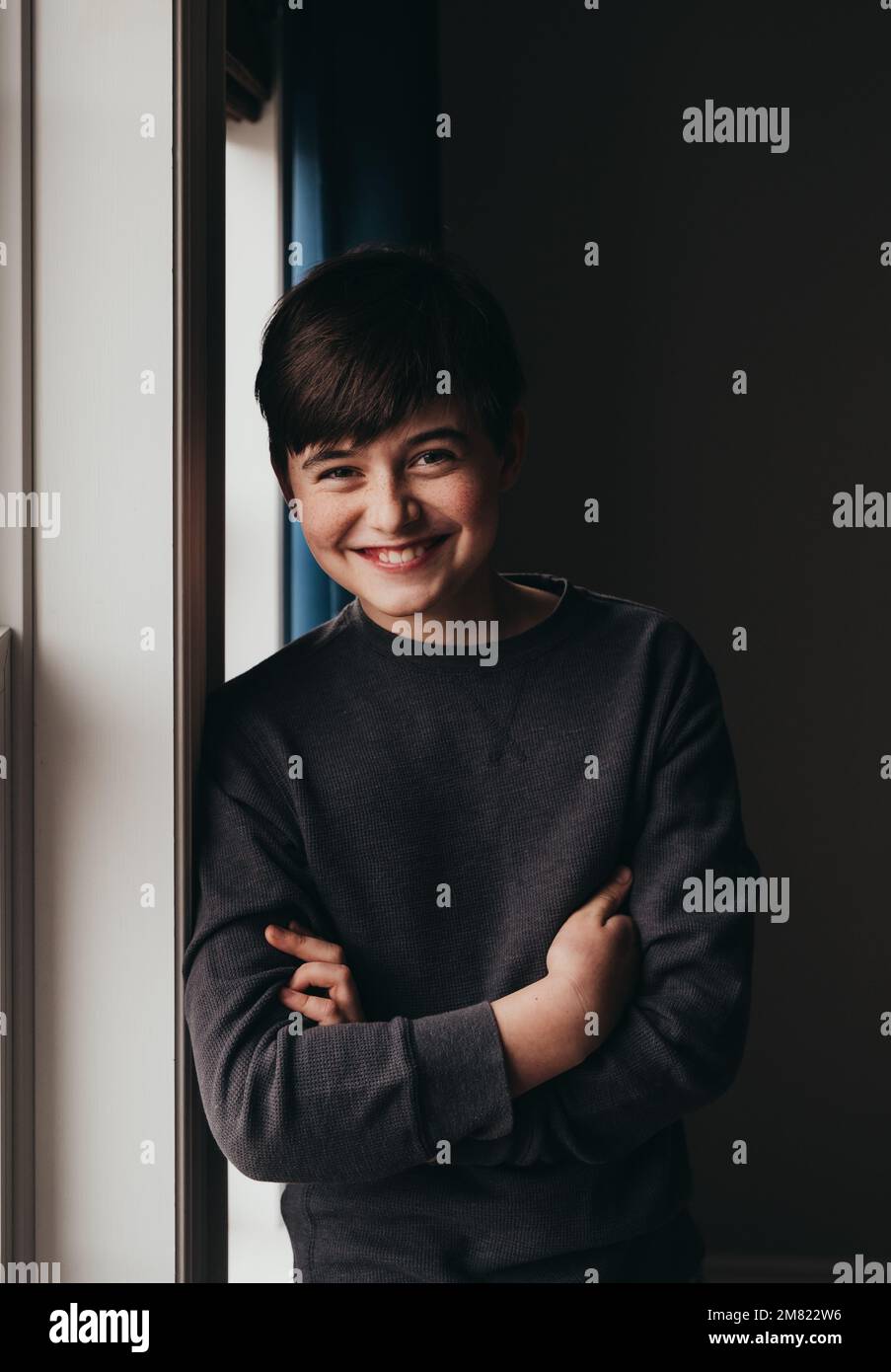 Portrait of happy smiling tween boy standing beside a window Stock ...