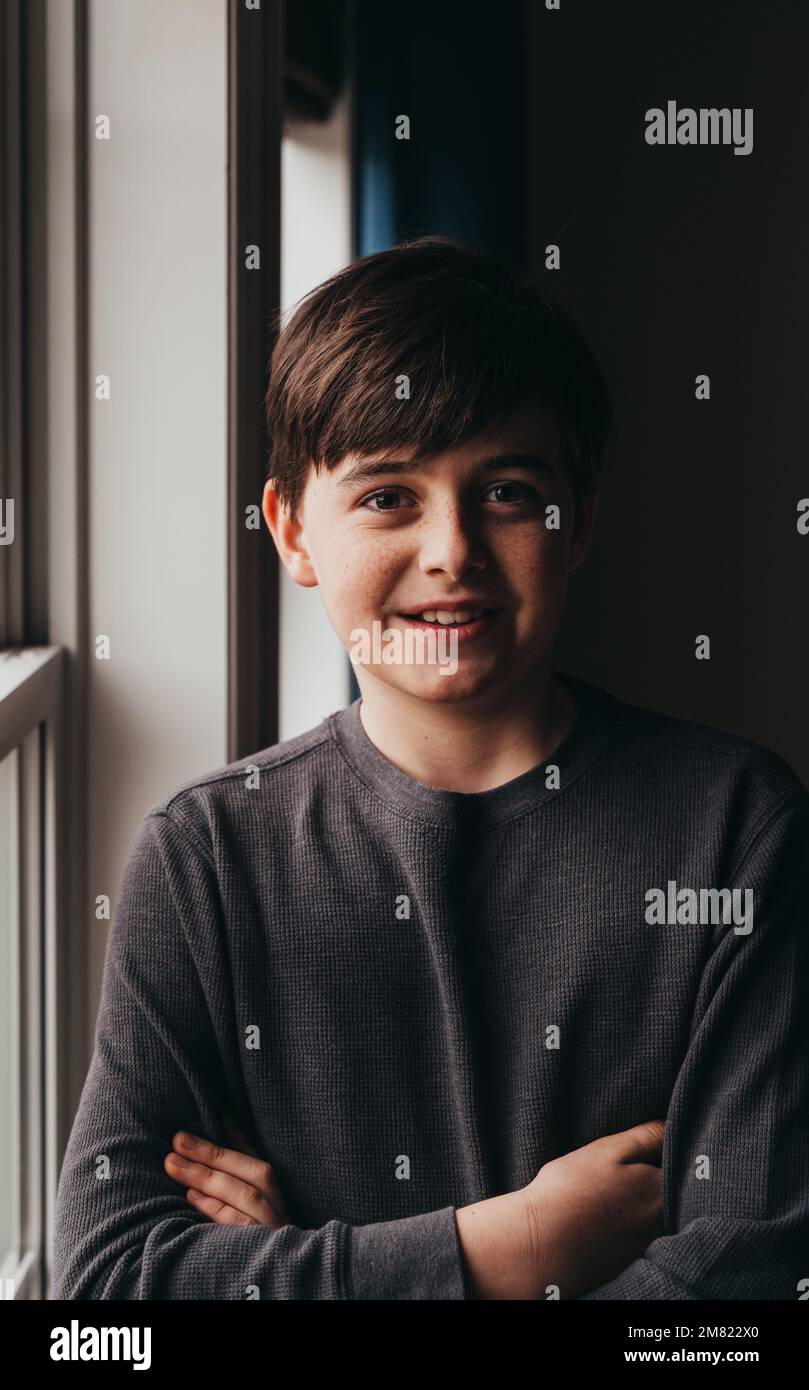Portrait of happy smiling tween boy standing beside a window Stock ...