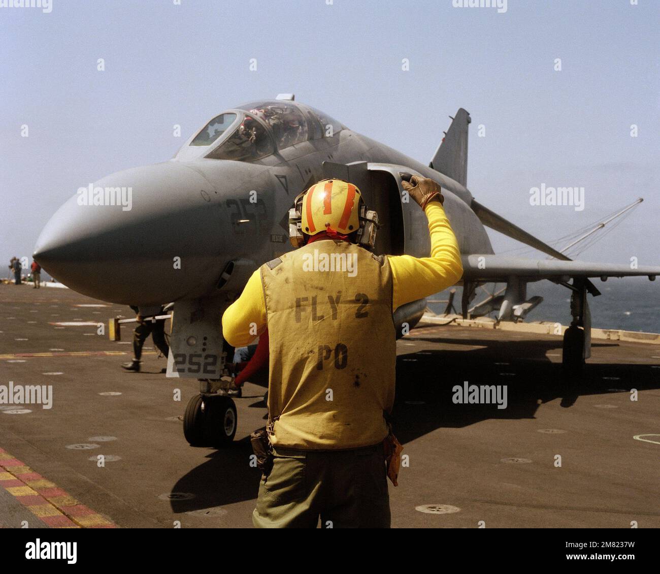 A plane director positions an F-4 Phantom II aircraft on the flight ...