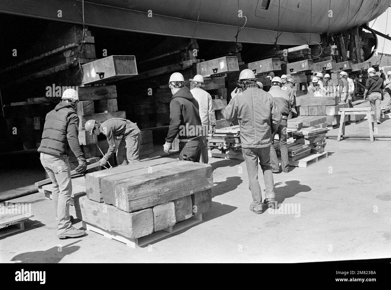 Shipyard workers remove support blocks from under the Safeguard class ...
