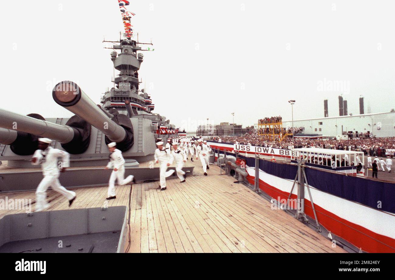 Crew members run to man the rails of the battleship USS IOWA (BB-61) as ...