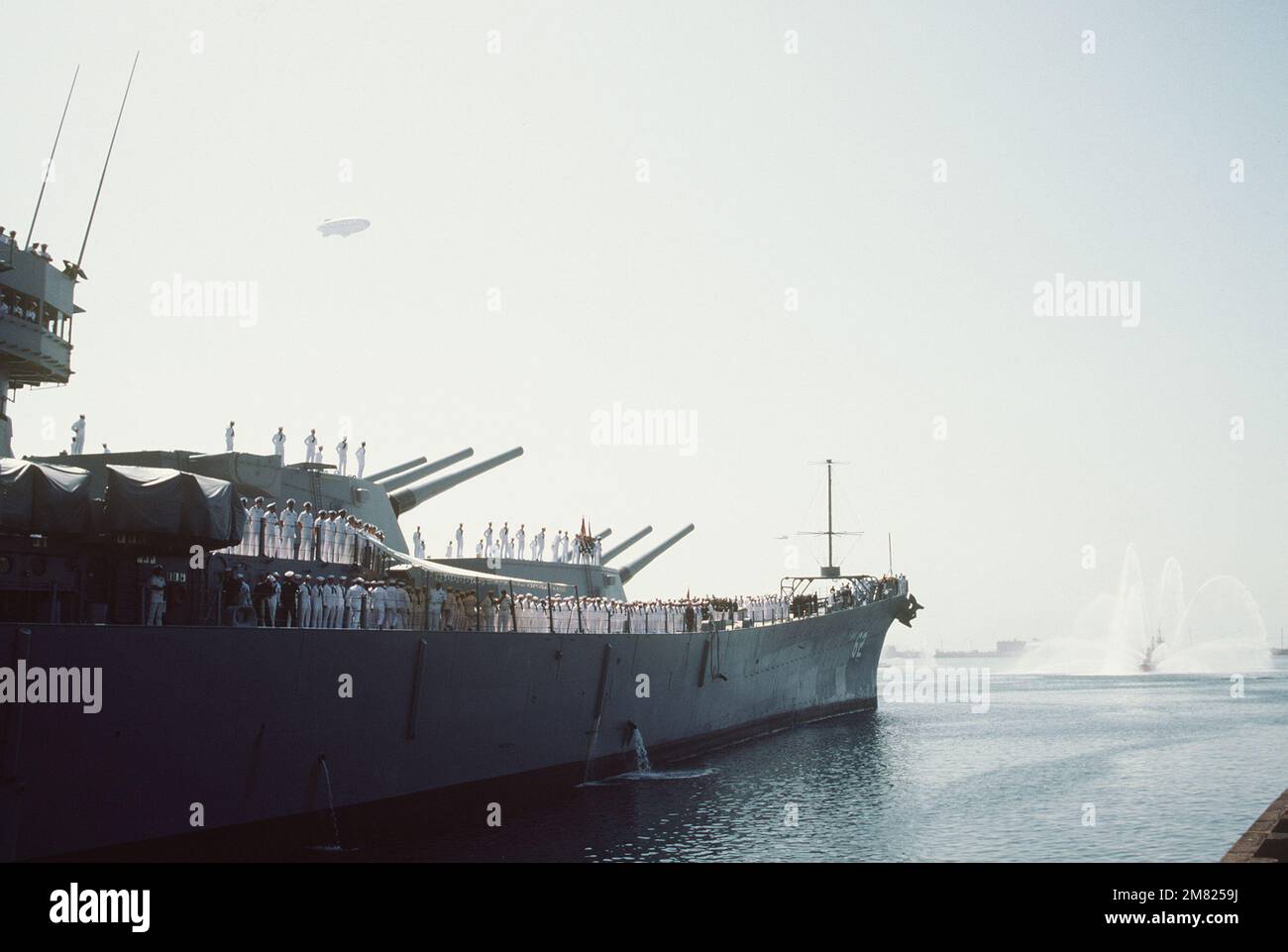 Crewmen man the rails and stand atop the forward 16-inch gun turret as ...