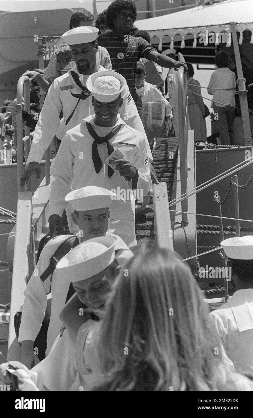 Crew members and their loved ones walk across the brow to go ashore ...