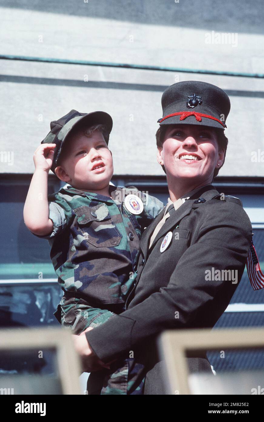 The wife and a son of Captain Mike Hicks, Marine Detachment, wait to ...
